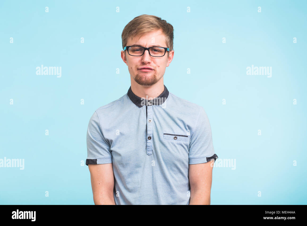 Young funny man wears spectacles isolated over blue background. Bearded ...