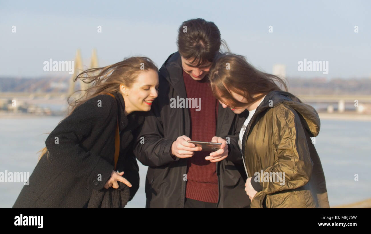 Young friends watching photos and laughing at the quay Stock Photo - Alamy