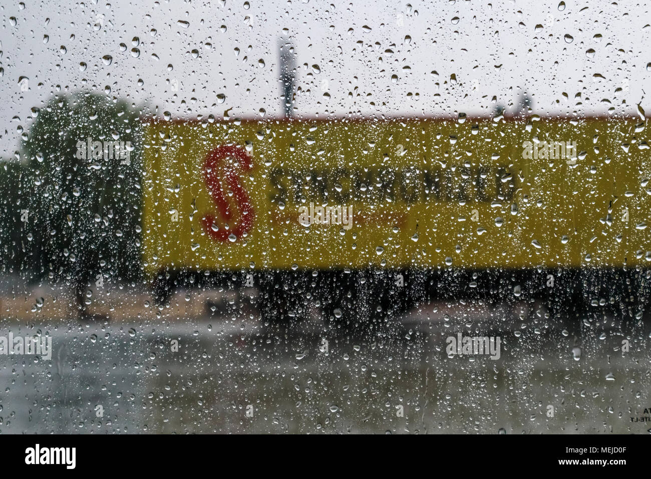 Raindrops on the outside of a car window with a yellow road haulage ...