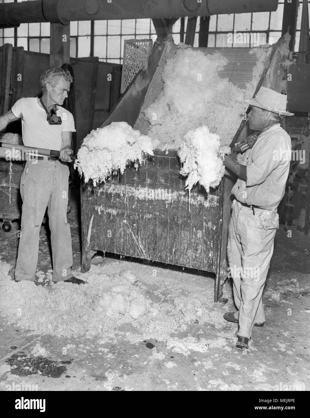 A worker watches an early industrial plastic manufacturing process in a ...