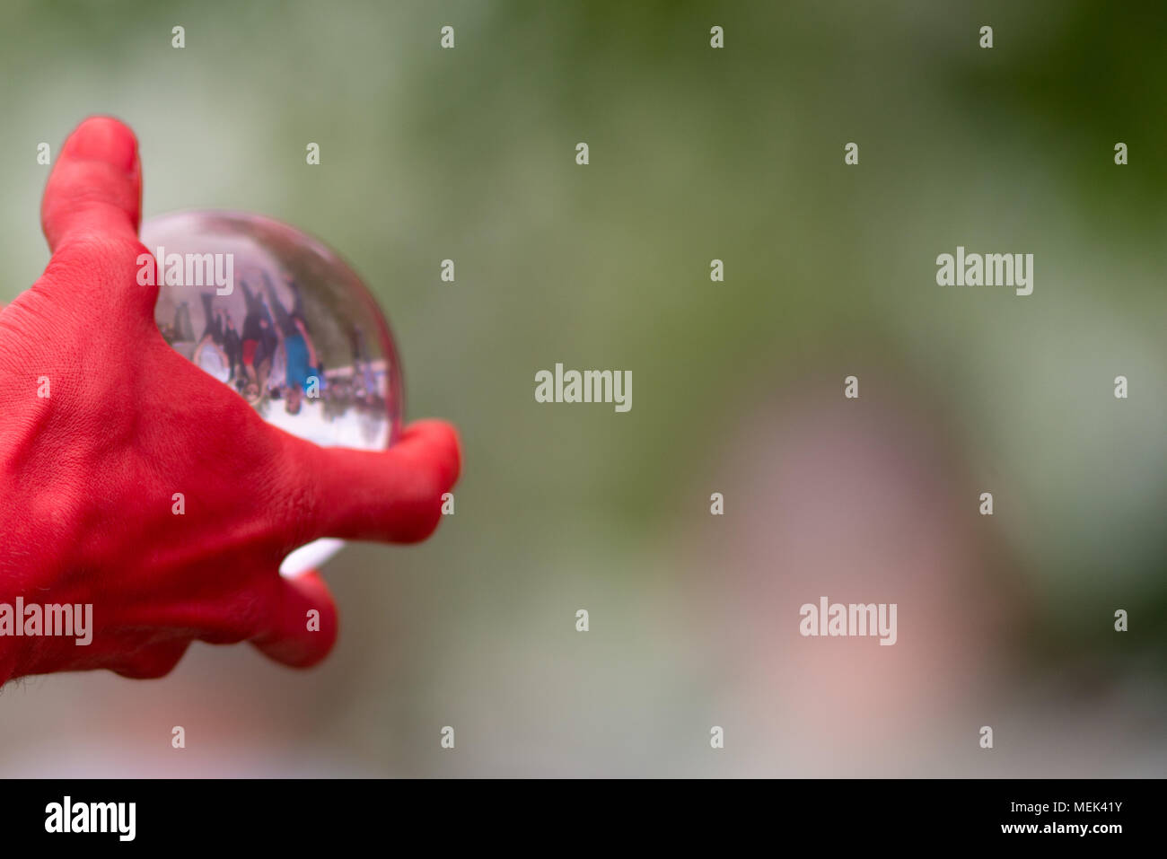 man with red hands dressed as the devil holds and plays with an ...