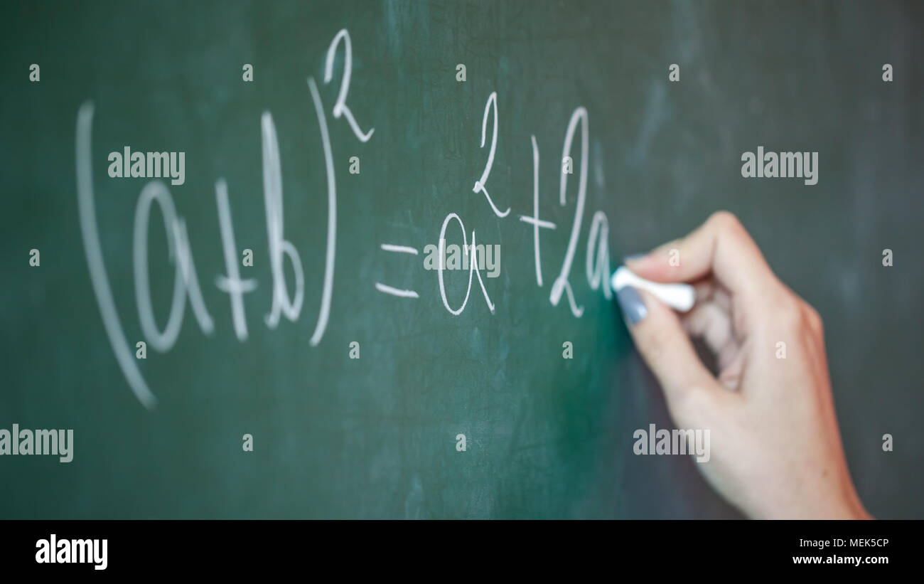 girl with chalk in her hand solves a mathematical problem on the ...