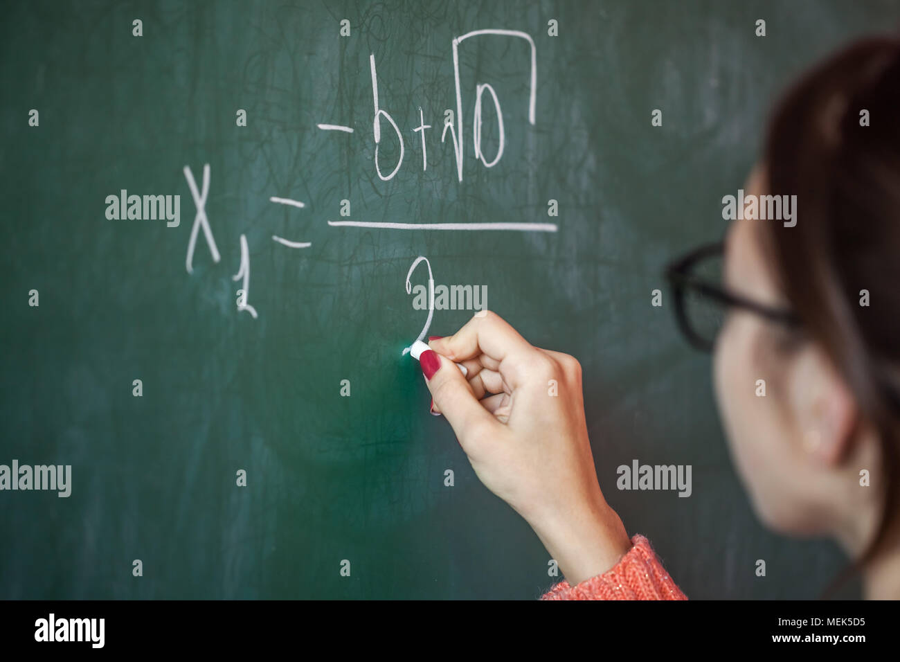 girl with chalk in her hand solves a mathematical problem on the ...