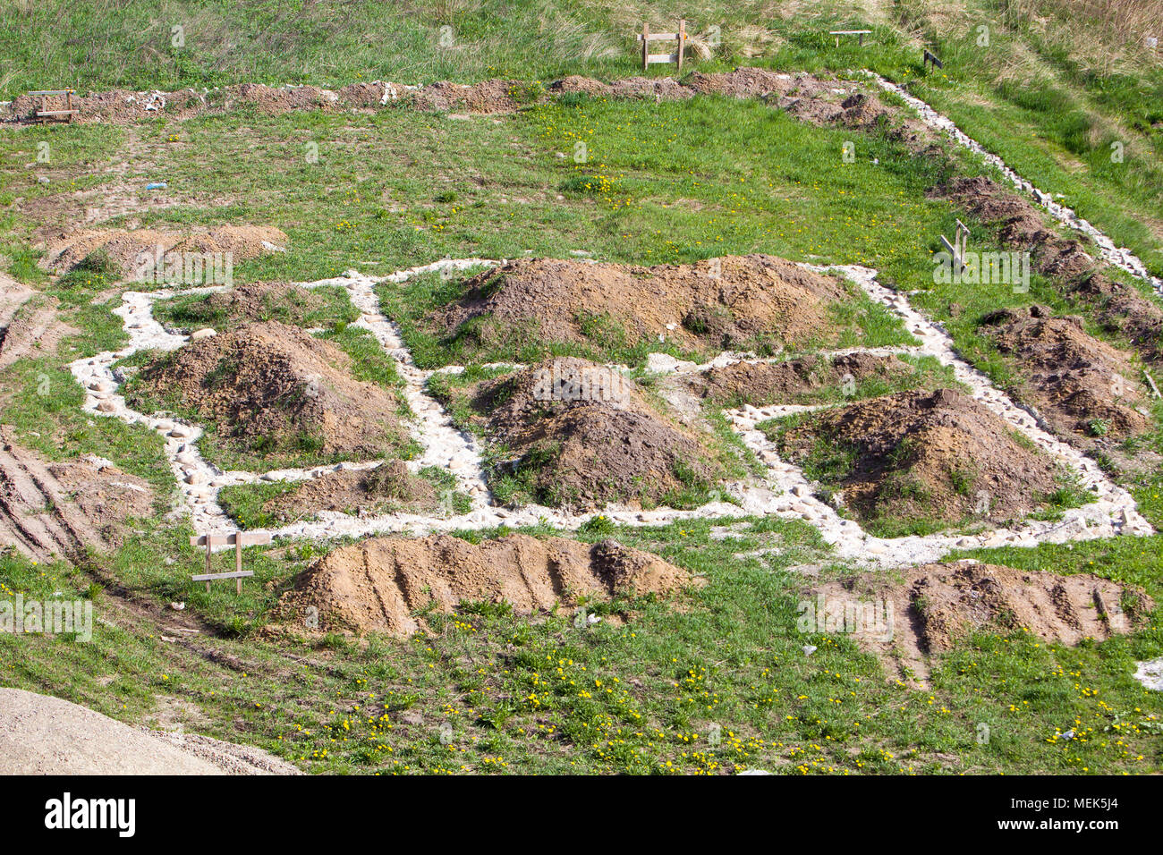 Building site in green field. Trenches dug in ground and filled with ...