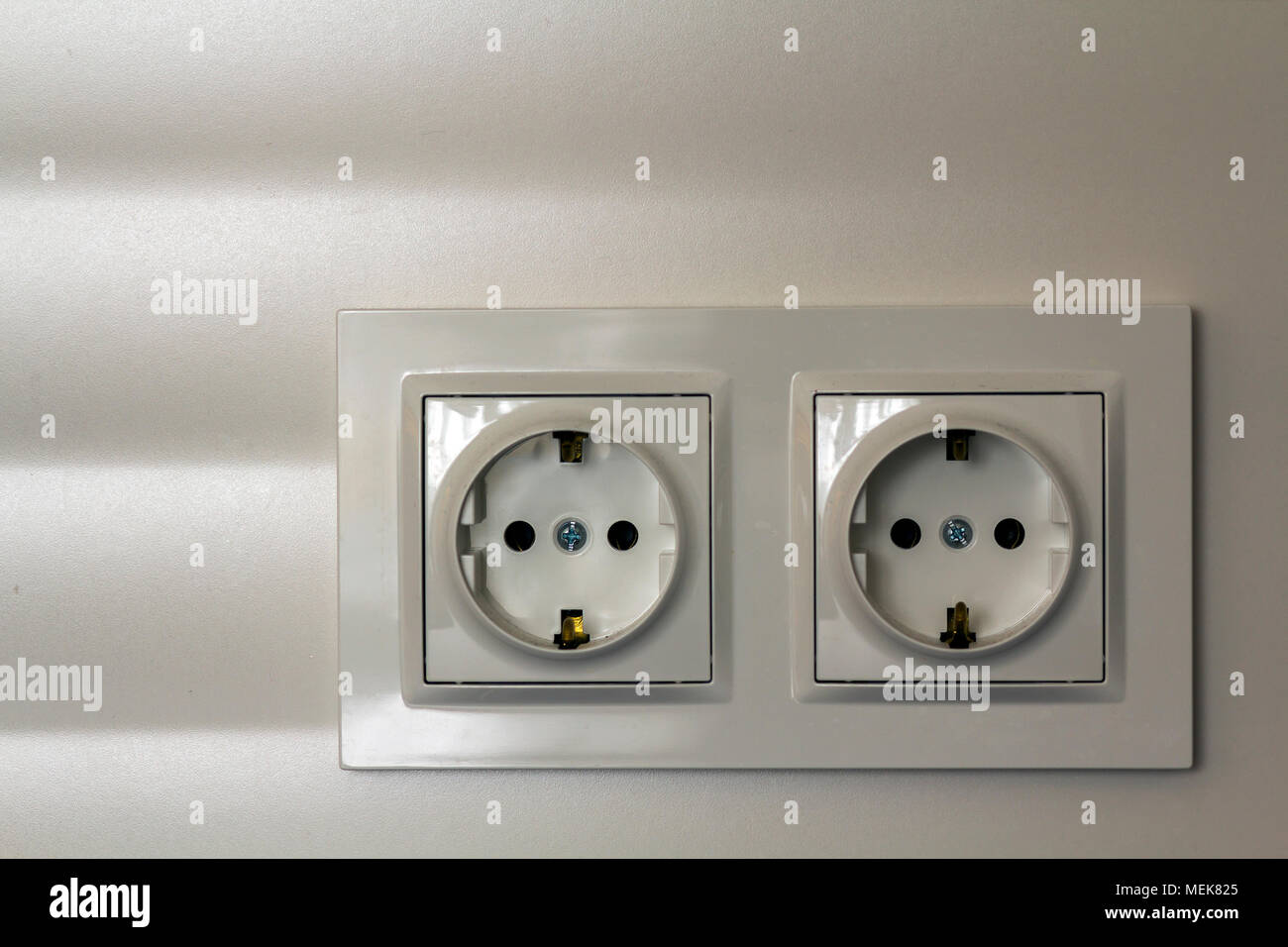 New white shiny plastic electric double sockets on white wall ...