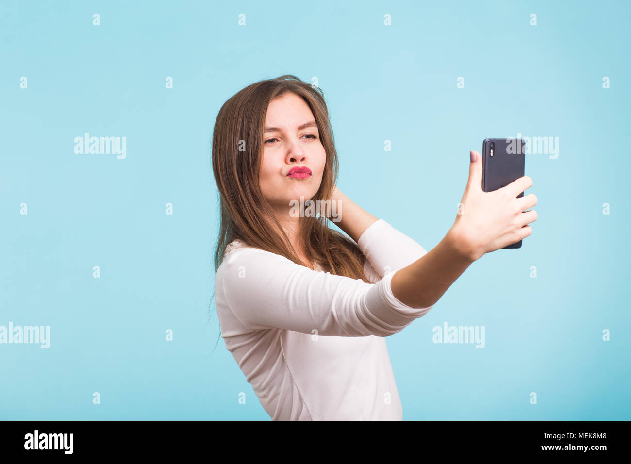 Beautiful girl taking selfie over blue background Stock Photo - Alamy