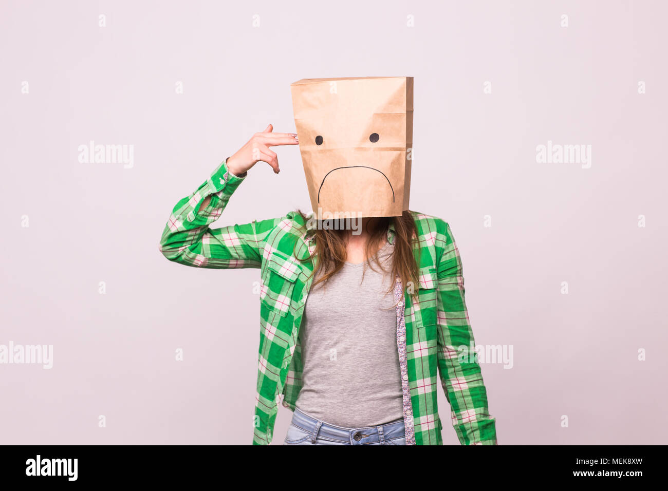 Unhappy girl with sad emoticon on paper bag on her head on white ...