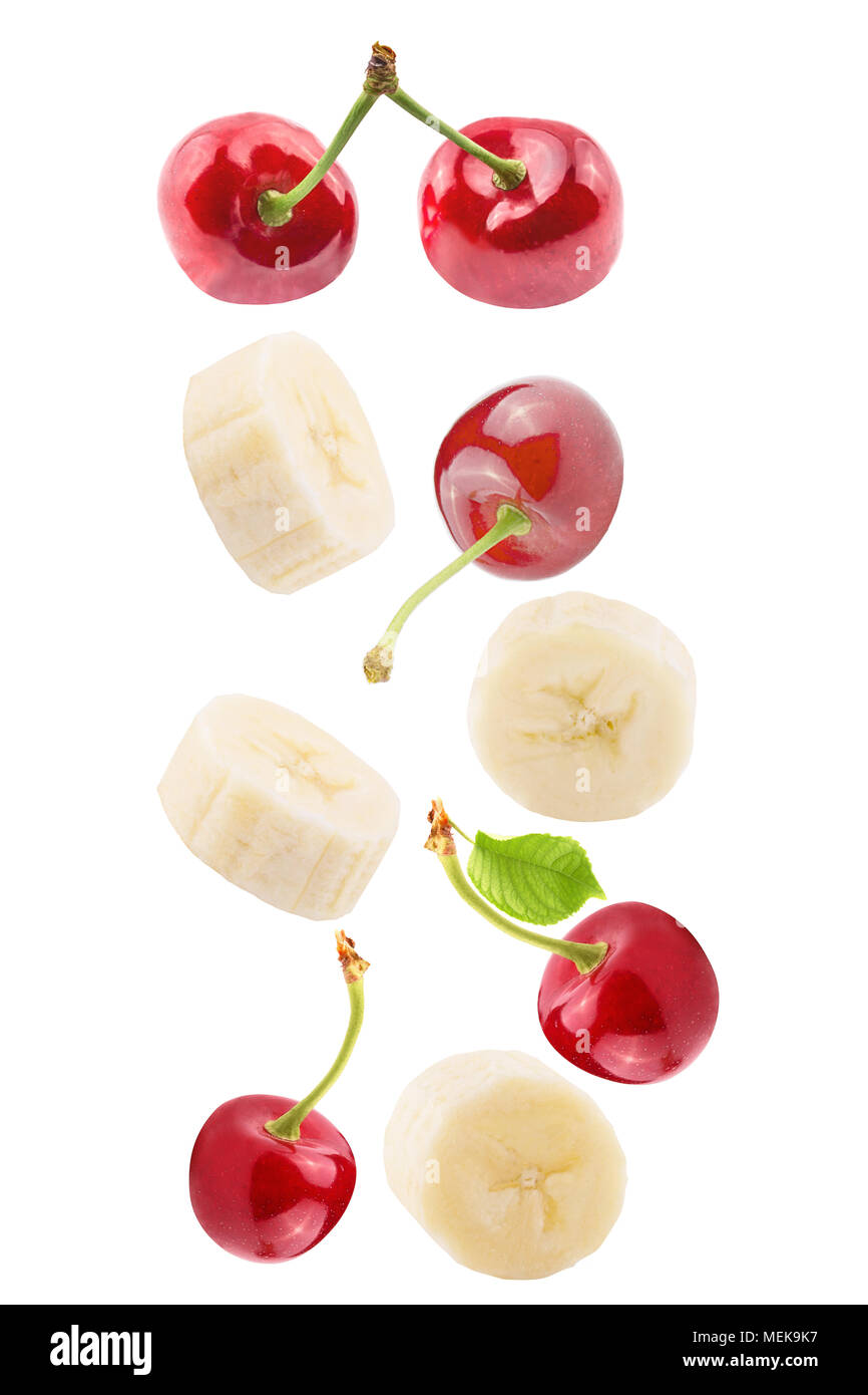 Isolated falling fruits. Falling sliced banana and cherries isolated on ...