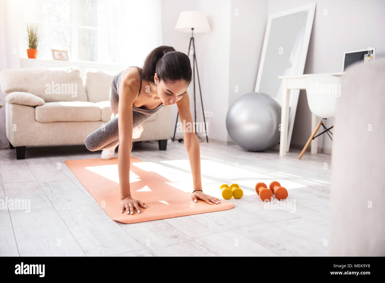 Slim woman doing plank with alternating side leg Stock Photo - Alamy