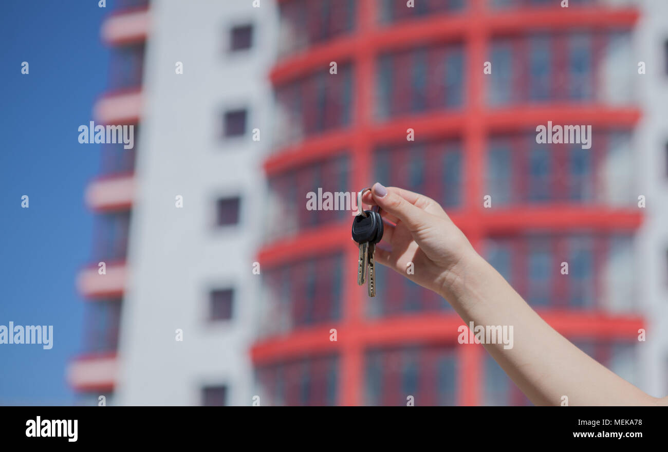 Female hand holding keys on the background of new house. Real estate ...