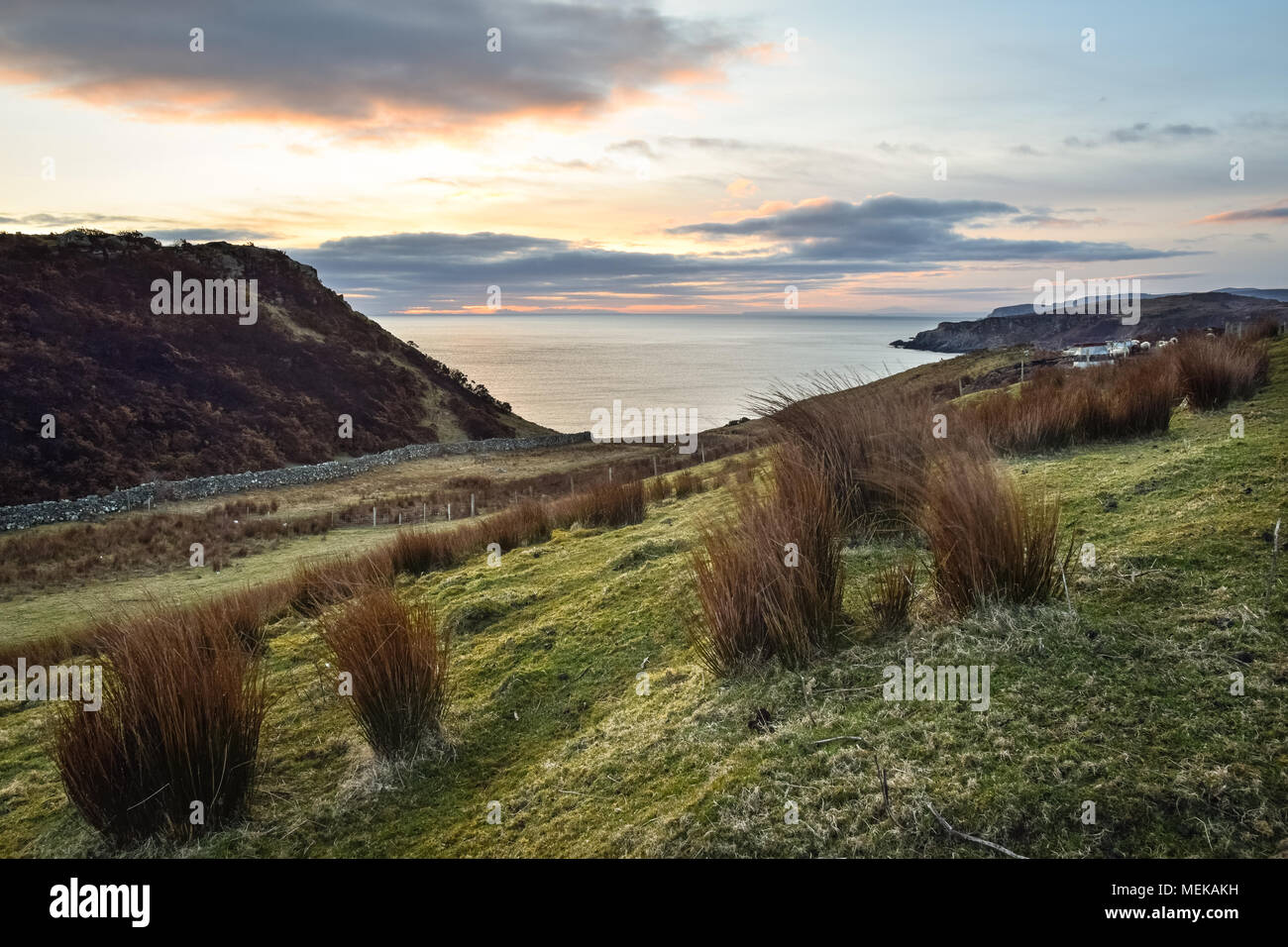 A grassy hill in Donegal Ireland over looking the ocean at sunrise ...