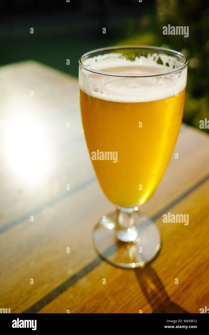 One cold light unfiltered beer in glass served on sunny outdoor terrace ...
