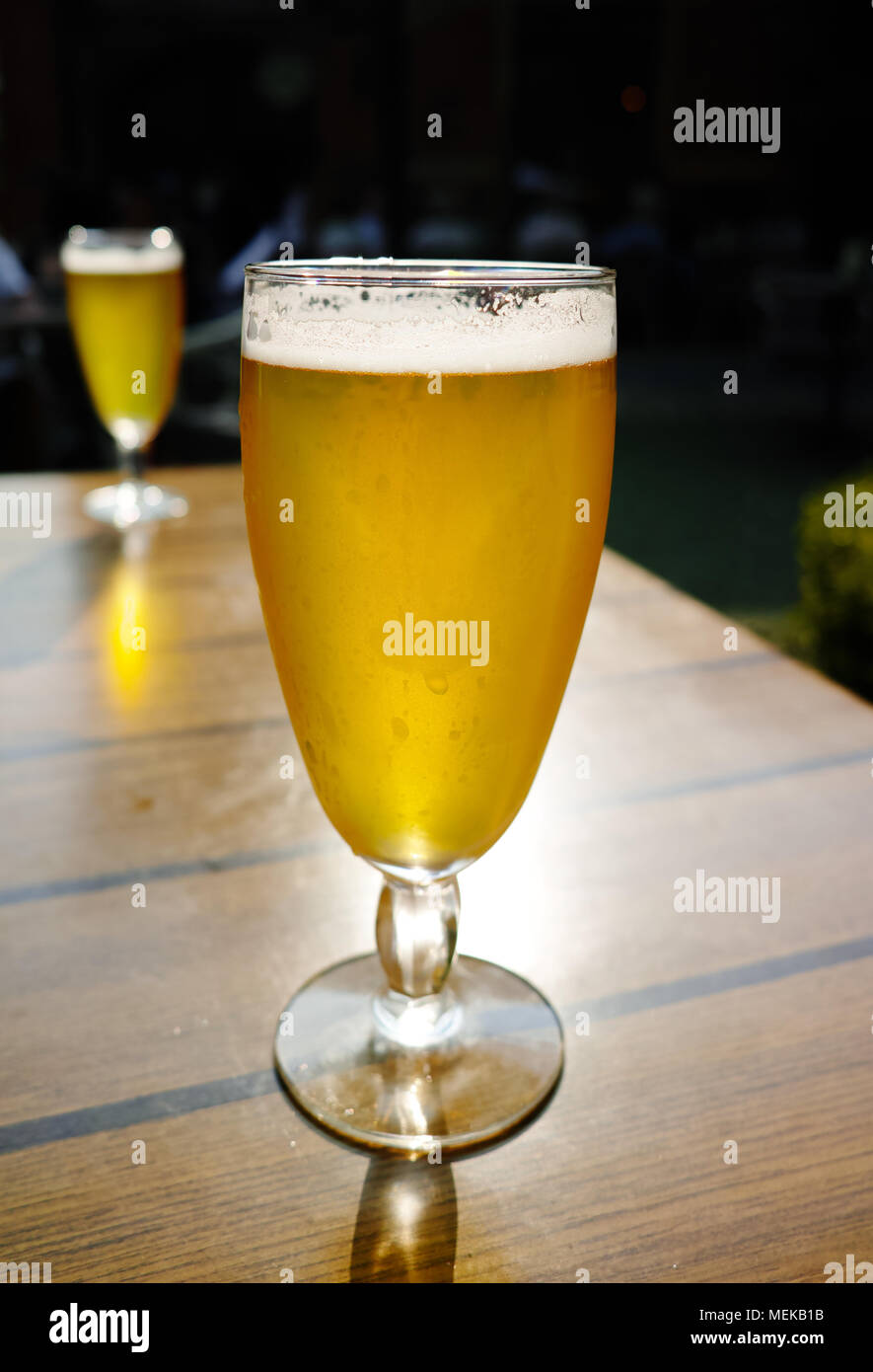 One cold light unfiltered beer in glass served on sunny outdoor terrace ...