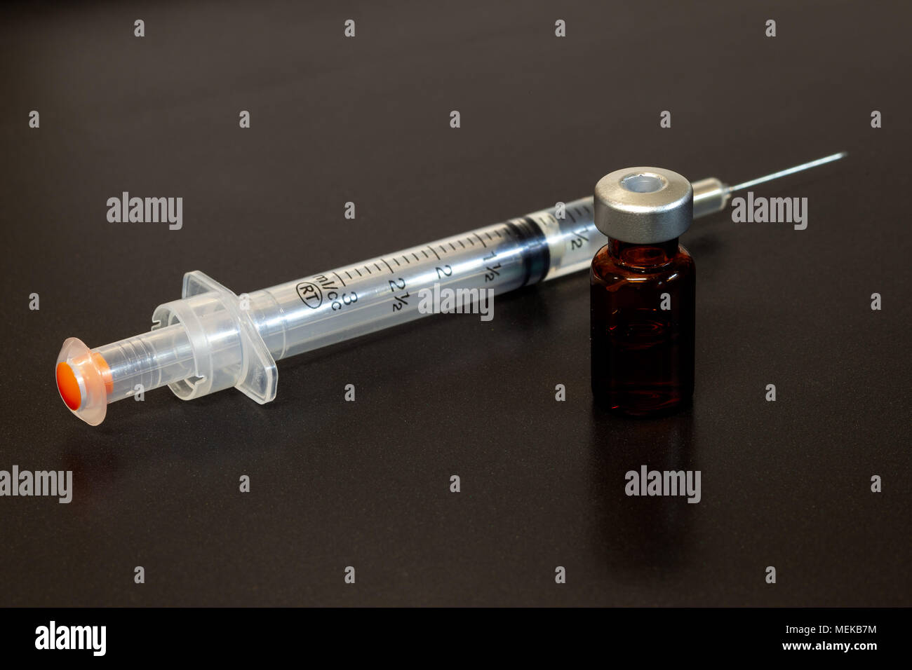 Medical Syringe and a vial of an intravenous drug on a dark background ...