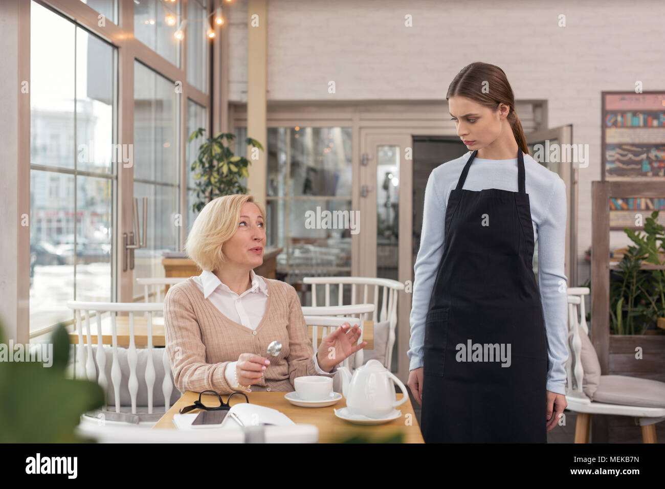 Serious waitress talking with her client Stock Photo - Alamy