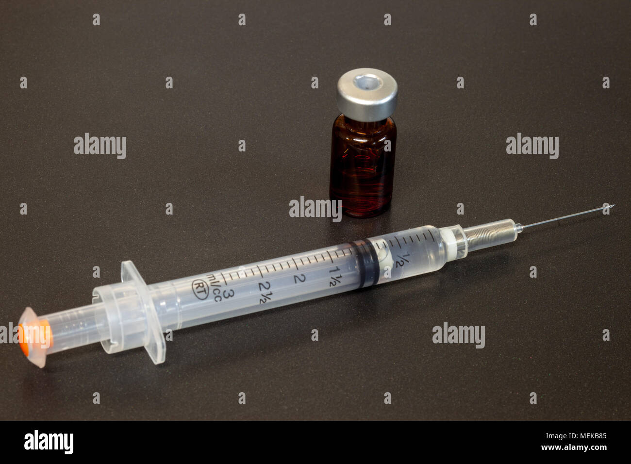 Medical Syringe and a vial of an intravenous drug on a dark background ...