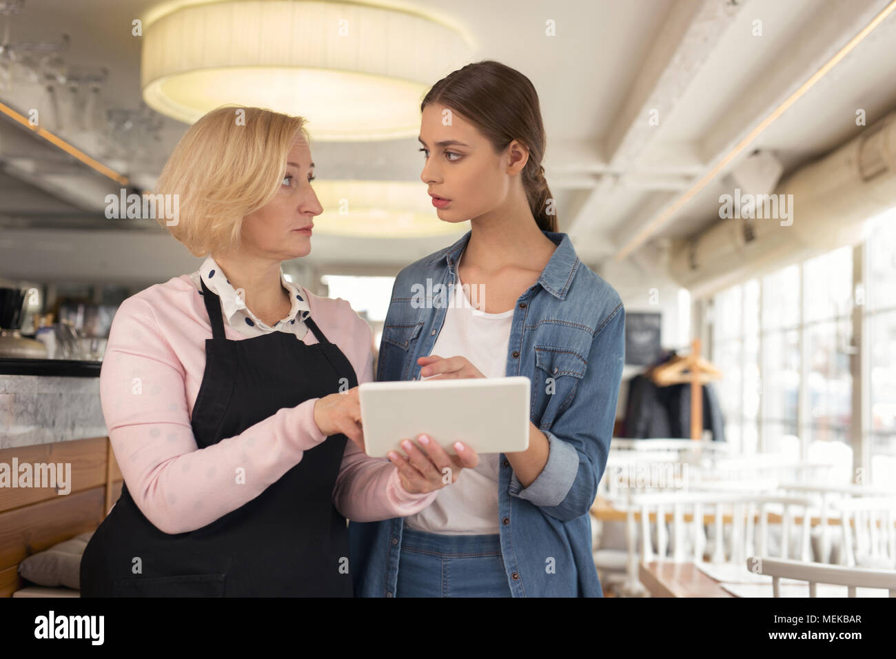 Serious waitress discussing work with her employer Stock Photo - Alamy