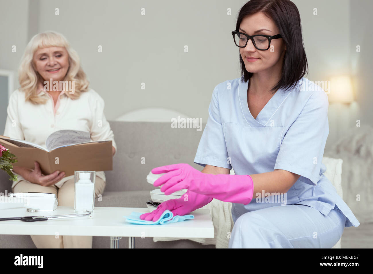 Concentrated female caregiver wiping dust Stock Photo - Alamy
