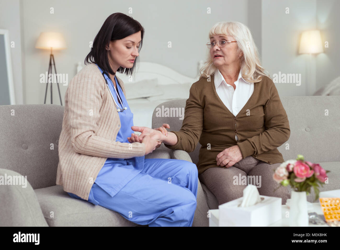 Focused female caregiver monitoring pulse Stock Photo - Alamy