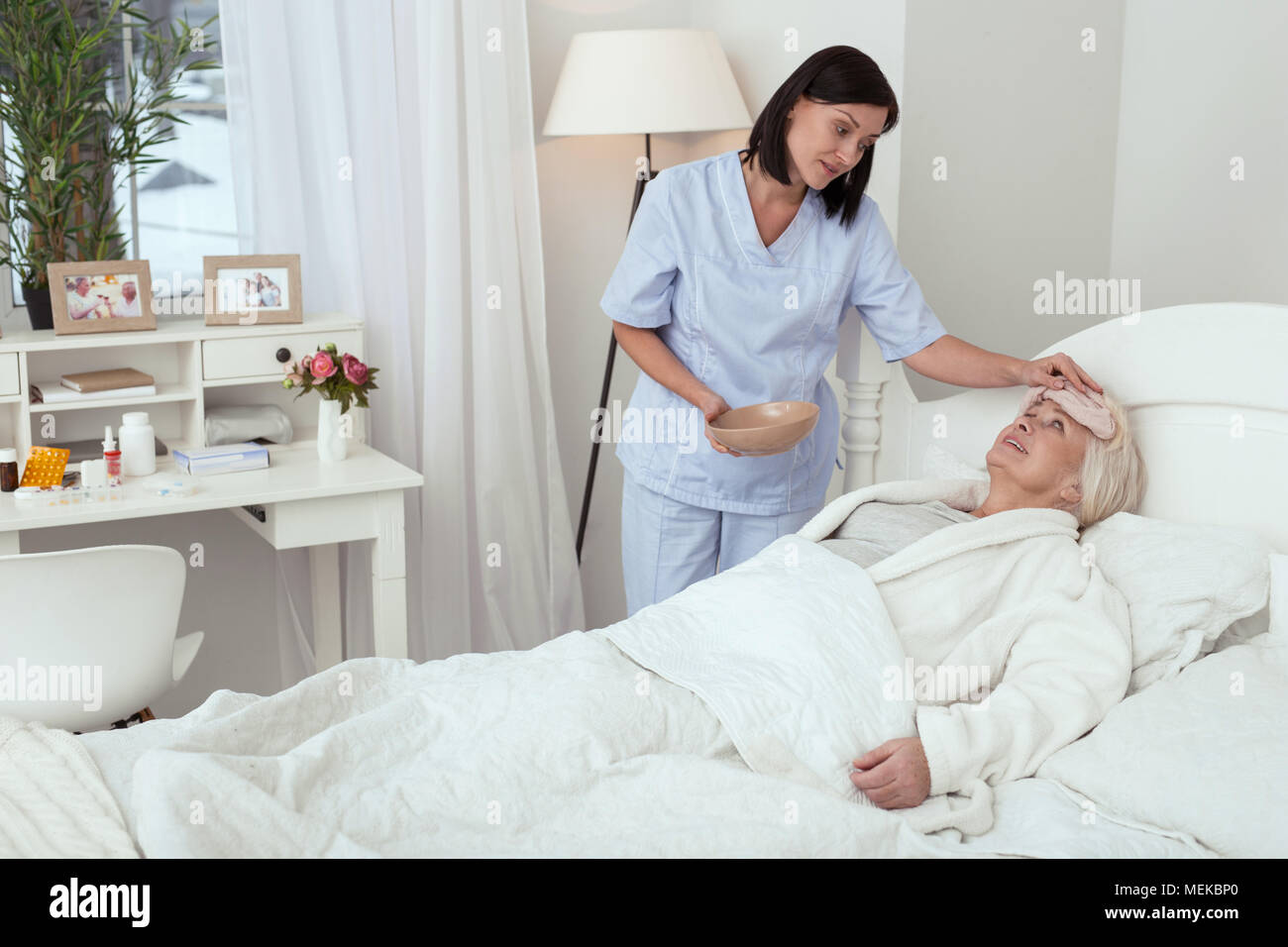 Uneasy worried caregiver reducing patient fever Stock Photo - Alamy