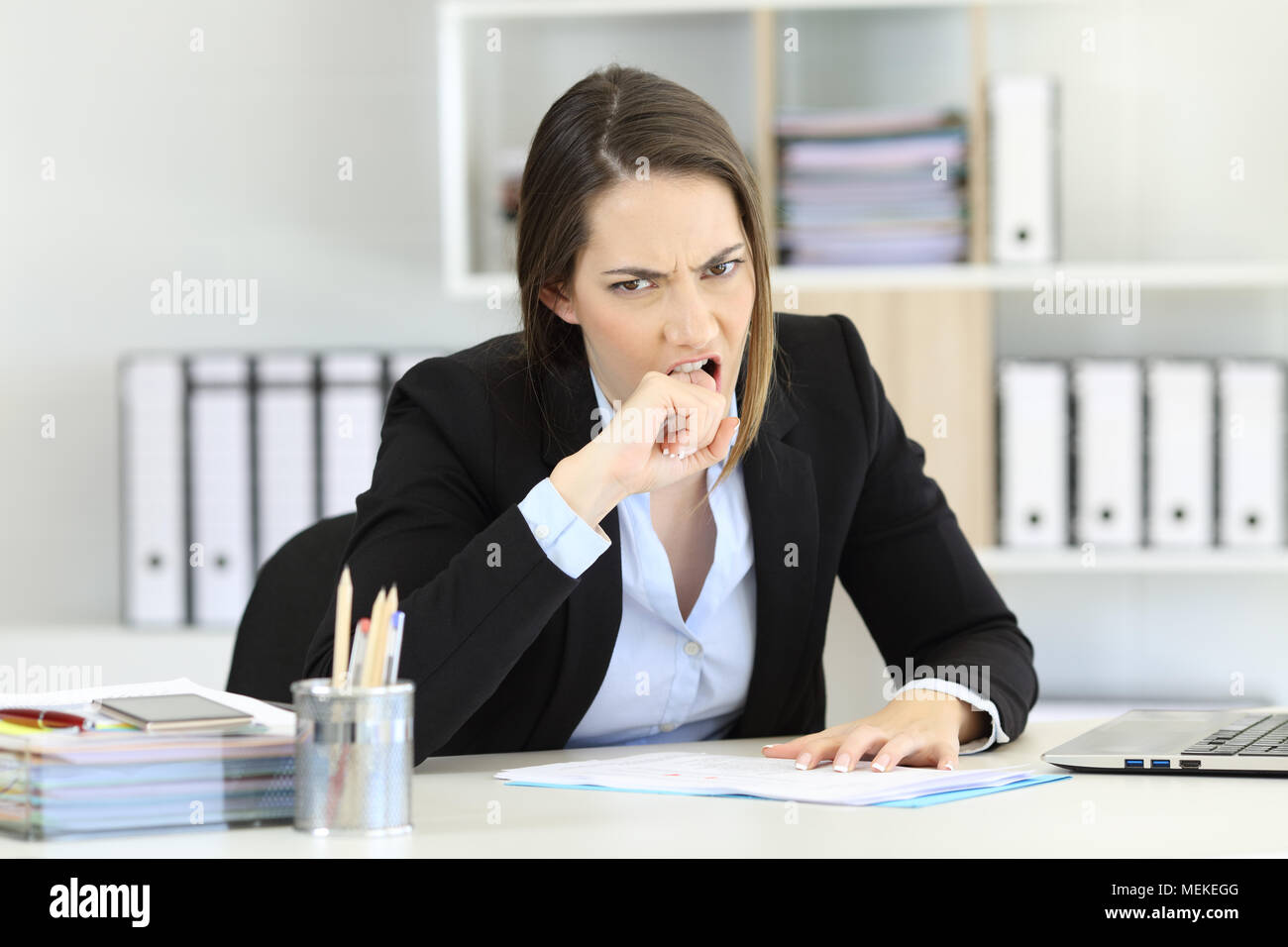 Angry executive sitting in a desktop looking at camera at office Stock ...