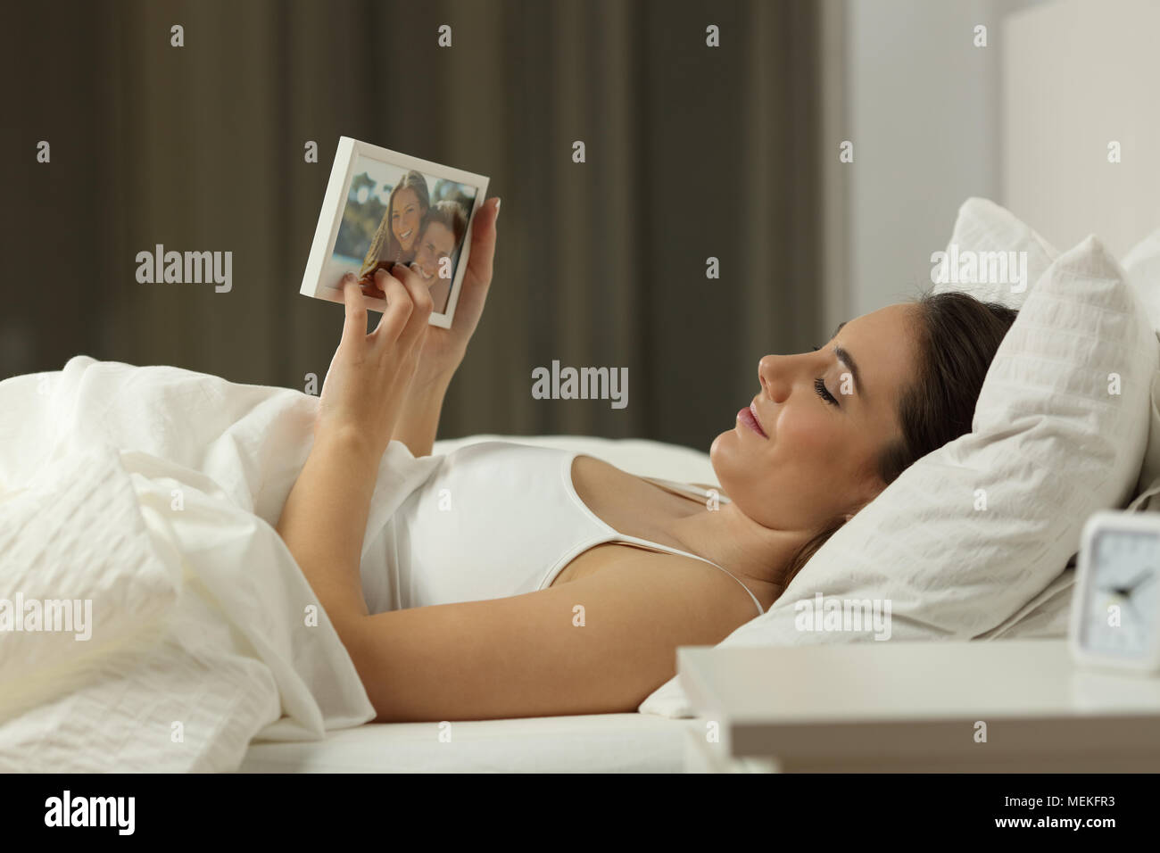 Side view portrait of a woman missing her boyfriend on the bed in the ...