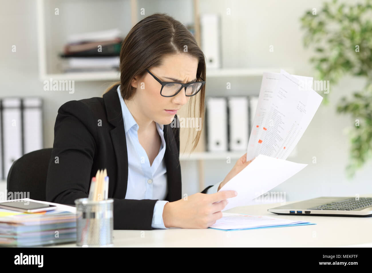 Worried office worker reading sales reports sitting in a desktop at ...