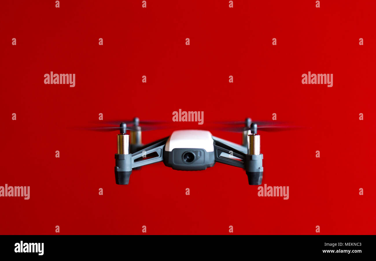 Toy drone flying indoor on a red background Stock Photo - Alamy
