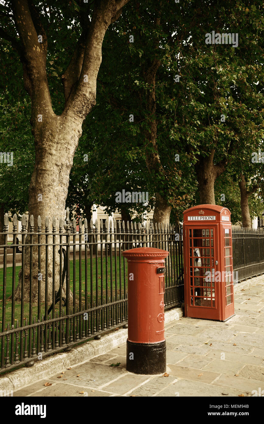 Red telephone and post box in street with historical architecture in ...