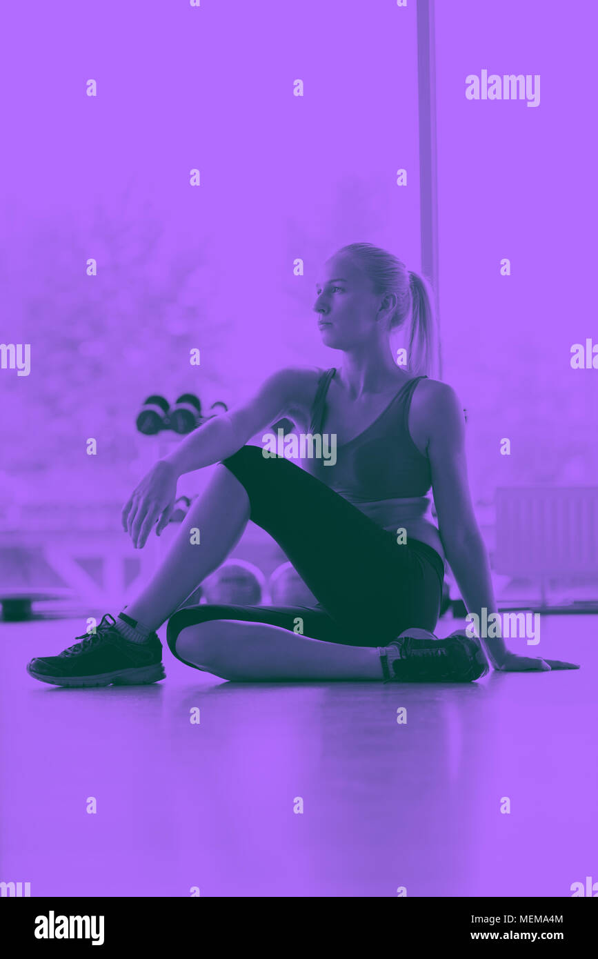 Cute young woman stretching and warming up for her training at a gym ...