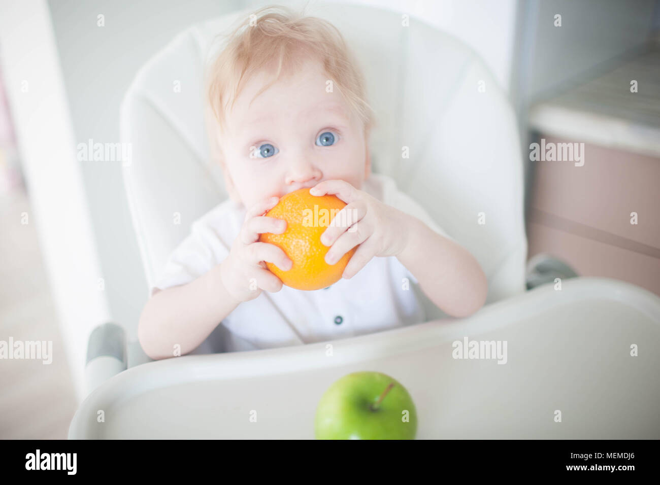 A baby boy in the kitchen eats fruit Stock Photo - Alamy