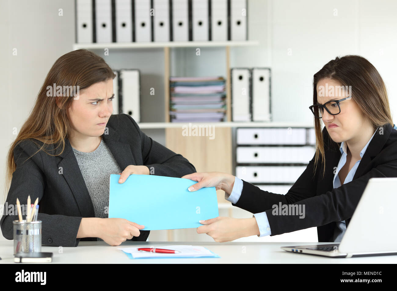 Two angry office workers fighting for a project sitting in a desktop at ...