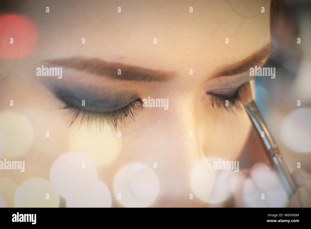 make up artist brushing on model’s left eye to make her beauty Stock ...