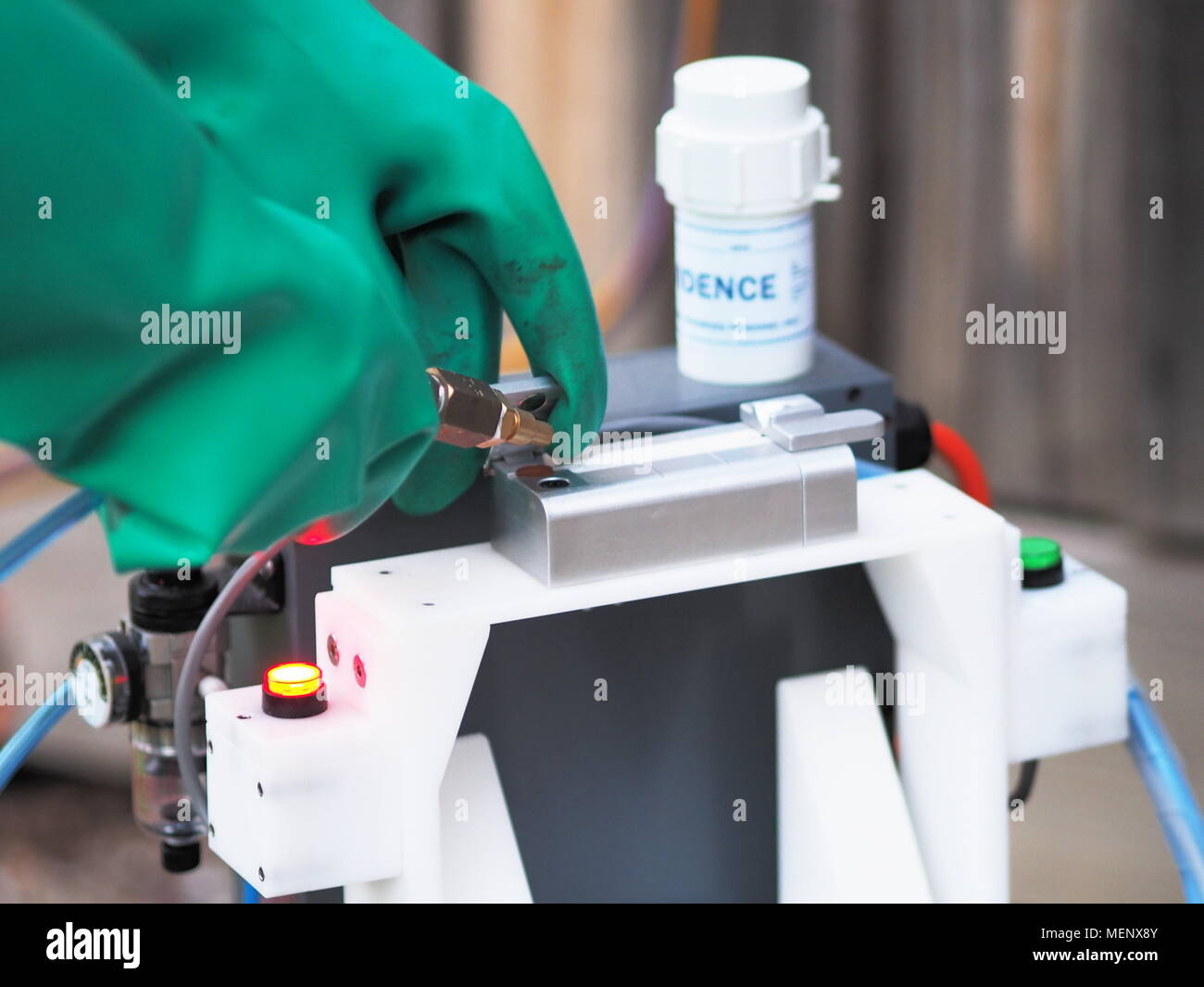Hand in protective gloves operates a device, image background shows a ...