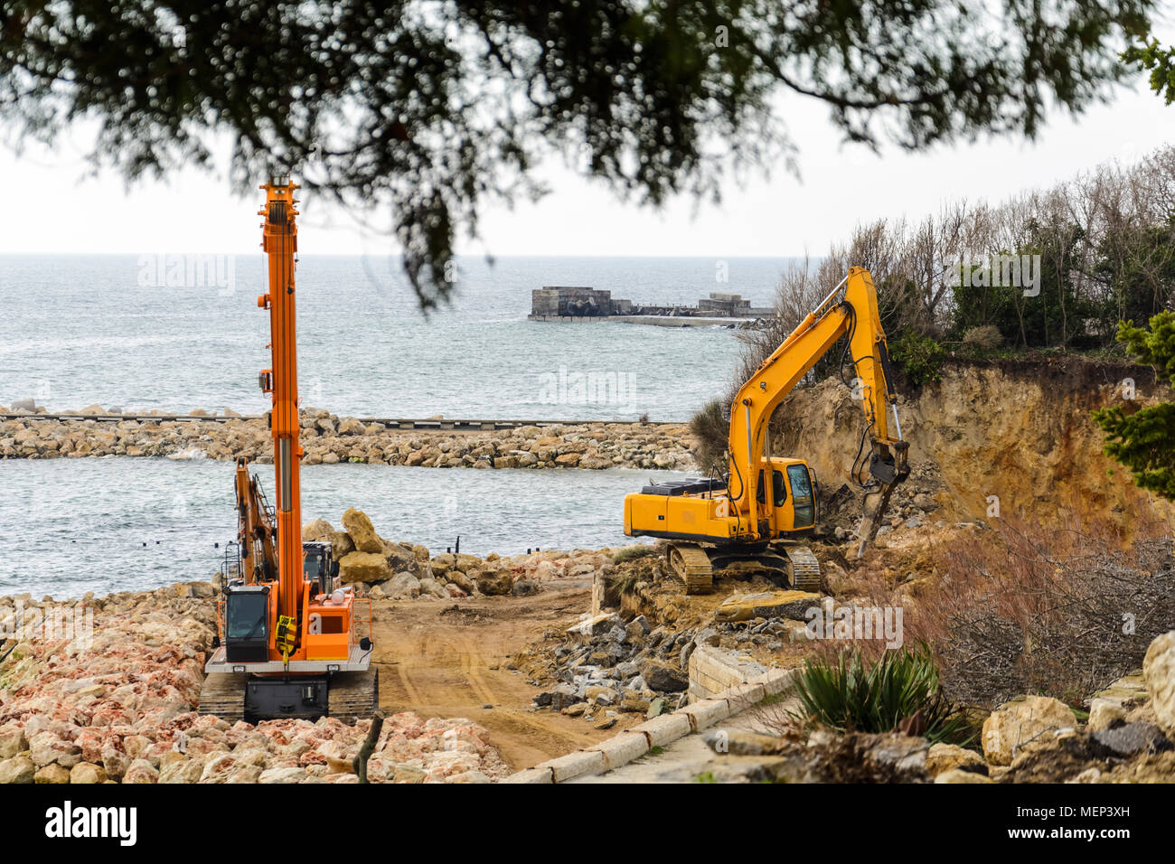 Excavator destroying a beach and a cliff for a hotel construction Stock ...