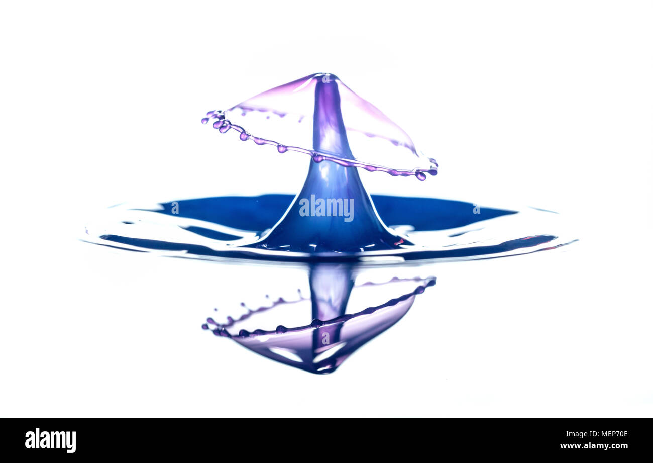 Splash and crown on rippled blue liquid or water surface . Water splash ...