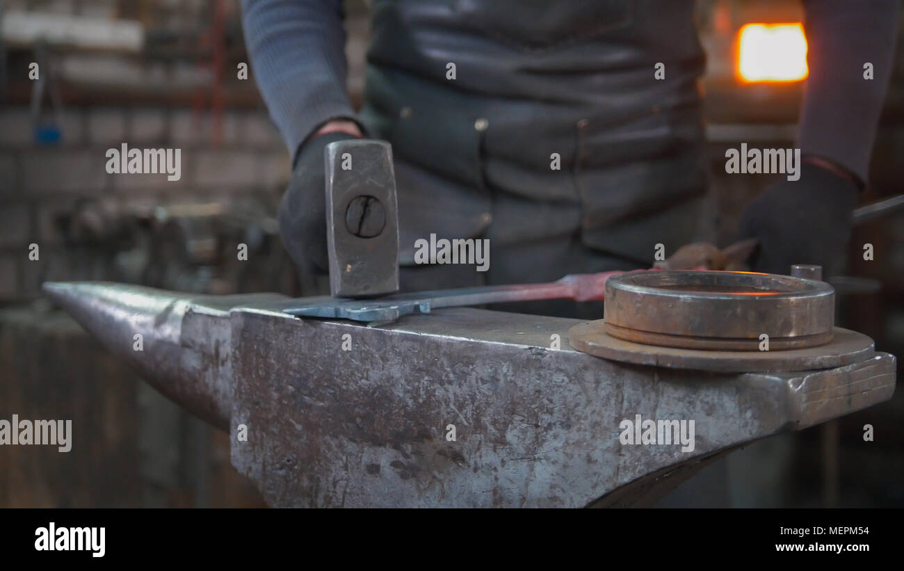 Muscular man blacksmith with hammer in forge creating steel knife Stock ...