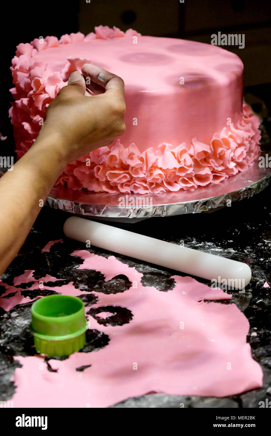 Decorating a cake pink icing flower petals are being place on home made ...