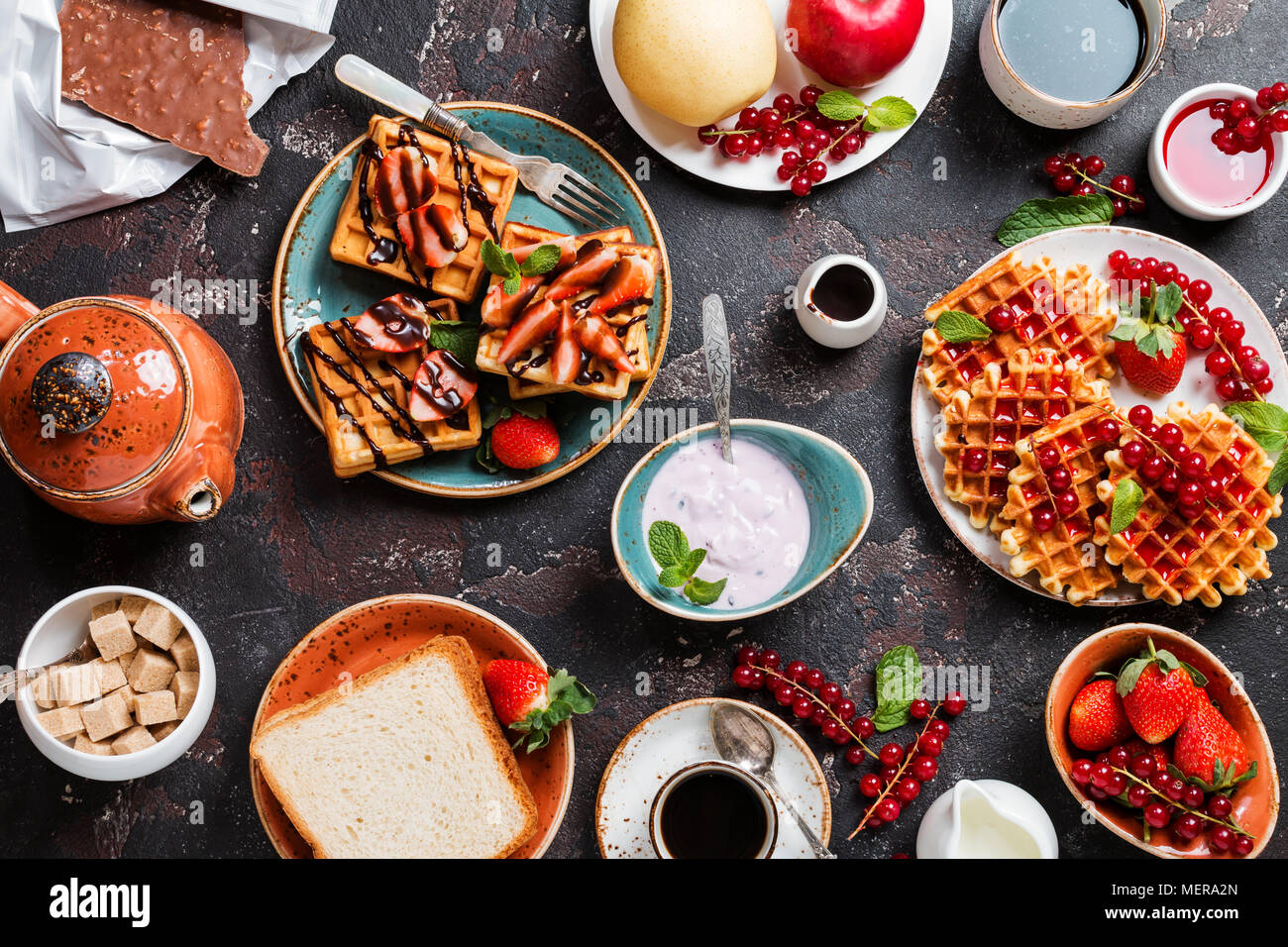 Breakfast table with waffles, yogurt, coffee and fresh fruits and ...