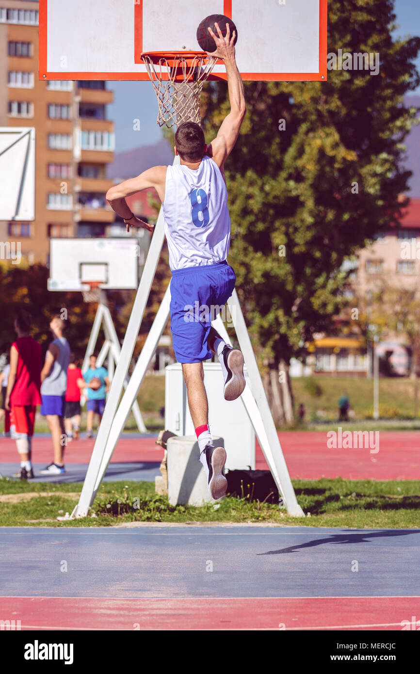 Street basketball player performing power slum dunk Stock Photo - Alamy