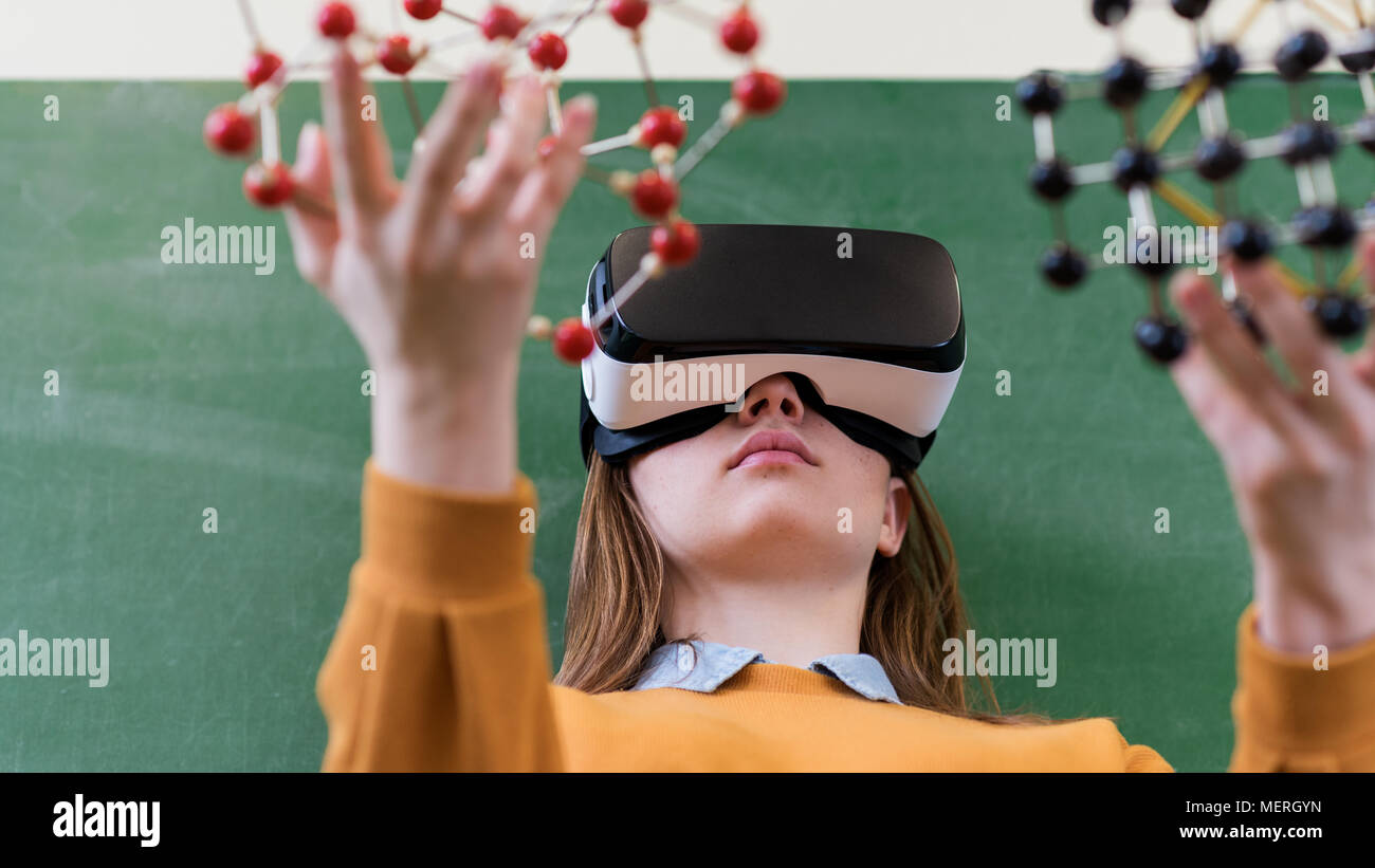 Female student wearing virtual reality glasses, holding molecular ...
