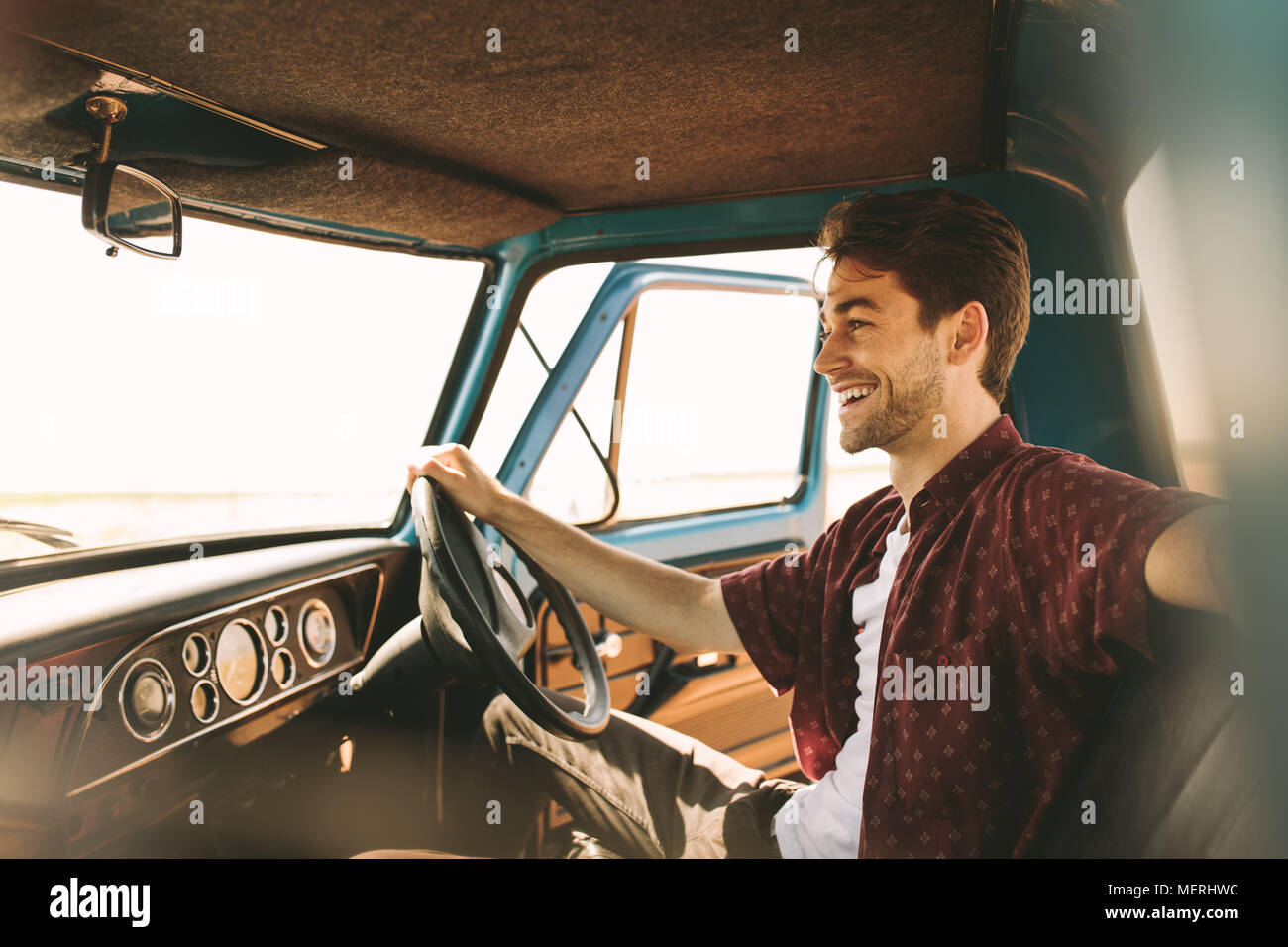 Smiling man sitting in the driver seat of an old car. Man sitting in ...
