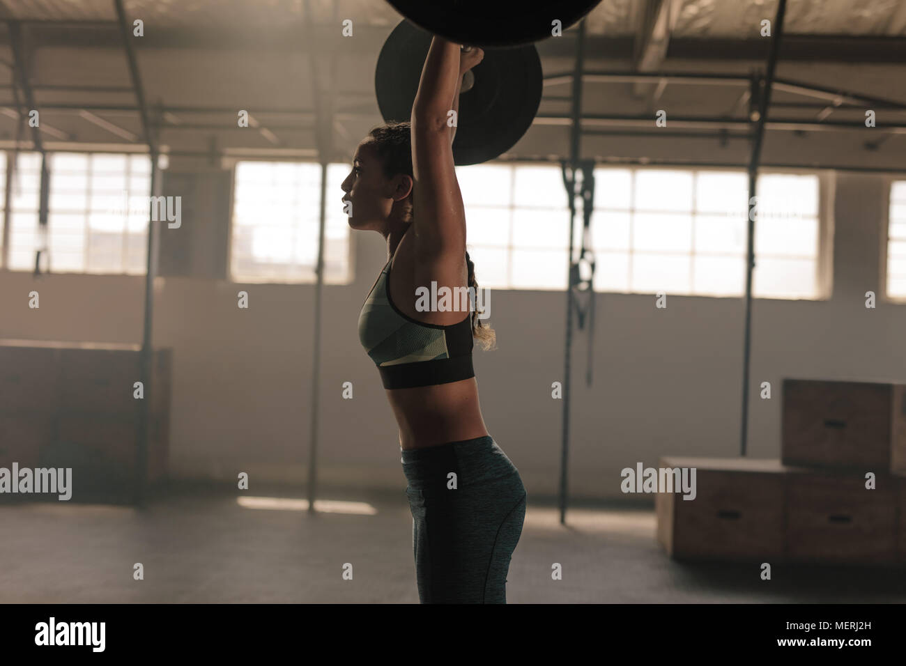 Fit young woman working out with heavy weights at cross training gym ...