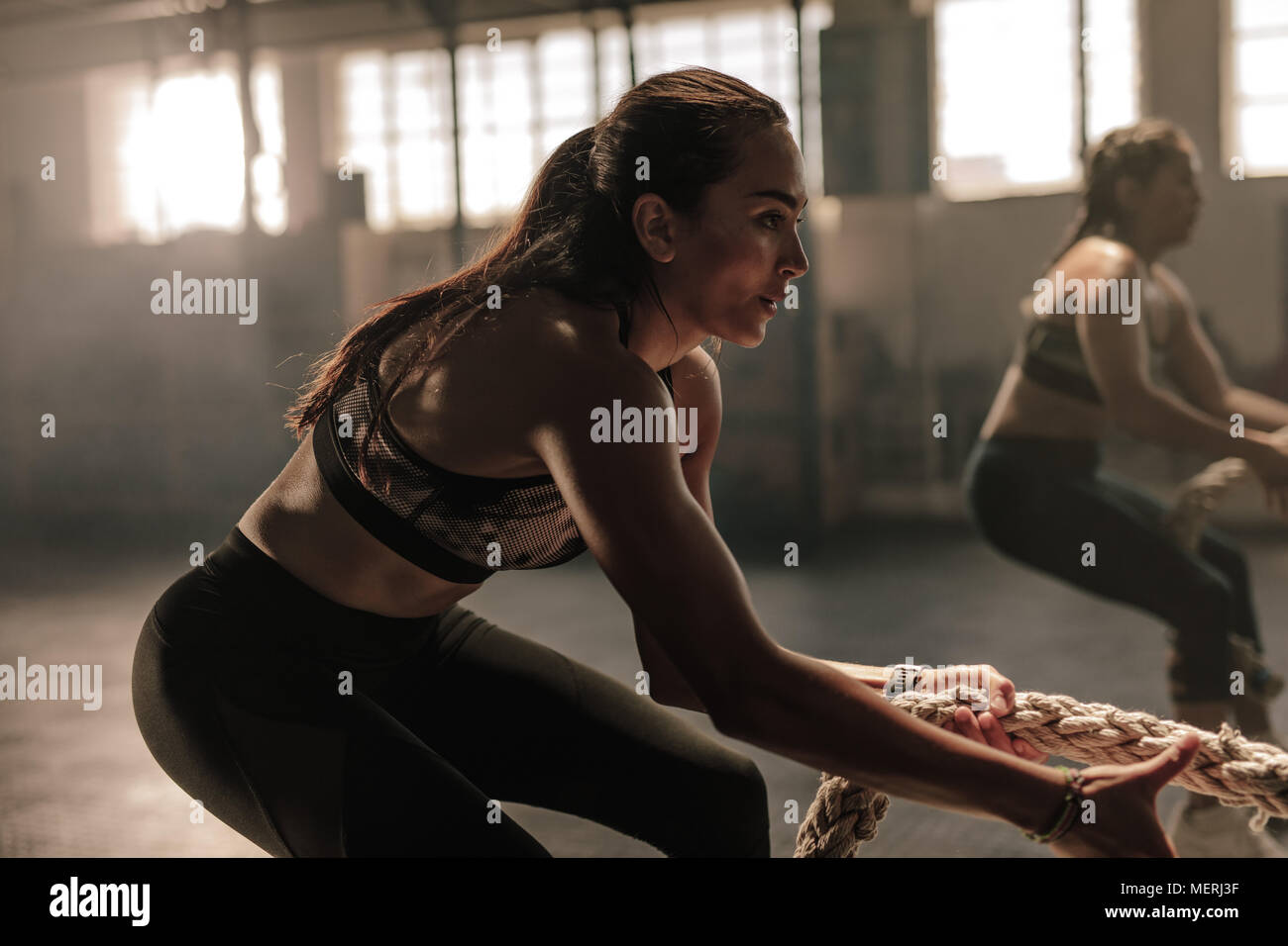 fitness females pulling rope at gym class. Two young women doing ...