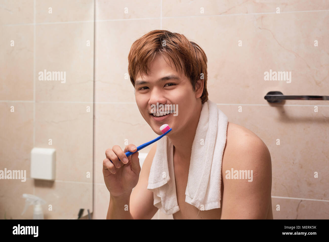 Brushing teeth in the morning. Attractive young man brushing teeth with ...