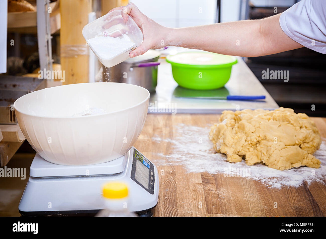 Close-up of a woman baker pouring a large spoon of white flour into a ...