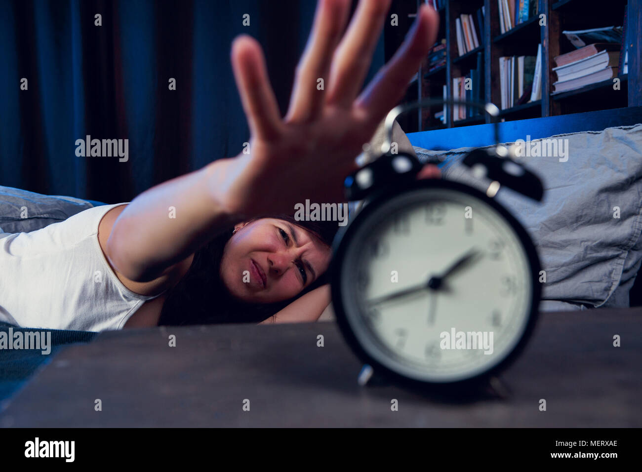 Photo of dissatisfied brunette with insomnia stretching arm to alarm ...