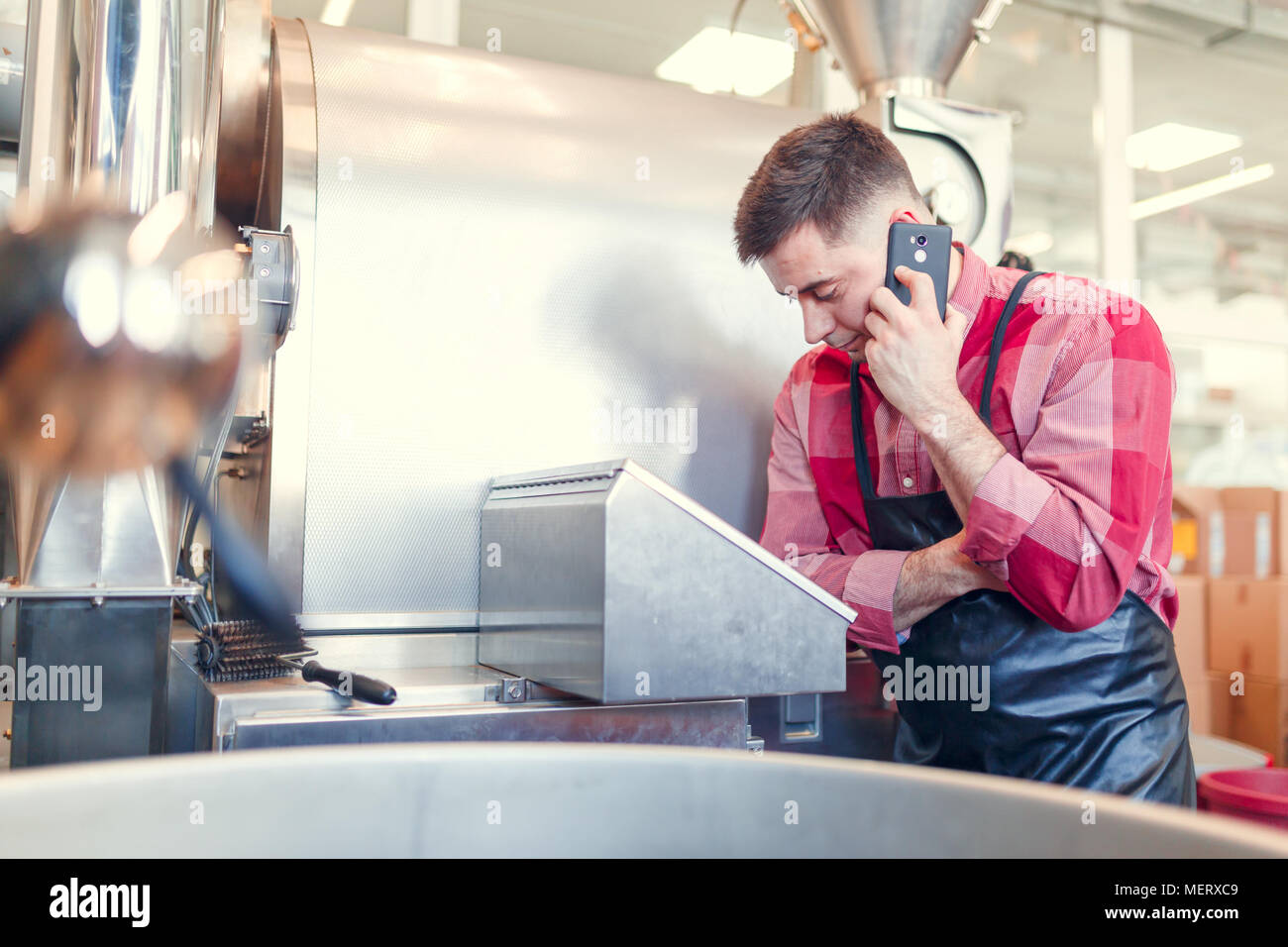 Image of businessman talking on phone at computer of industrial machine ...