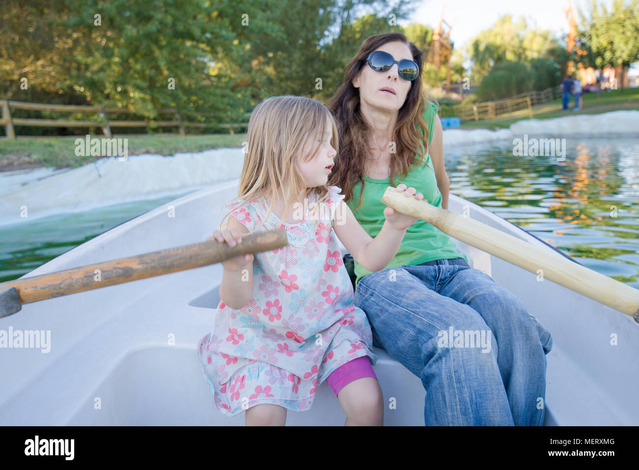 four years old blonde child paddling next to woman mother sitting in ...