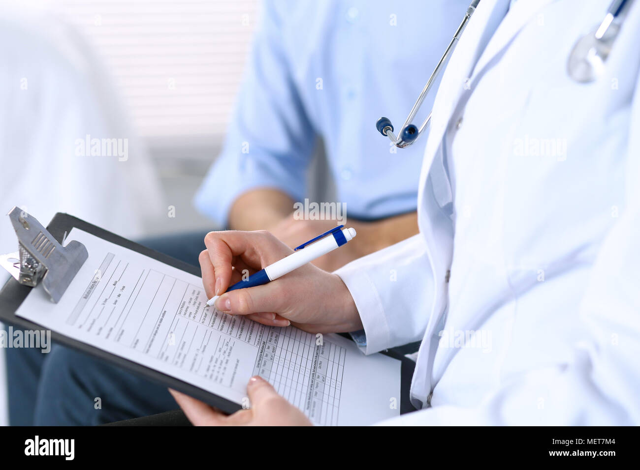 Female doctor holding application form while consulting man patient in ...